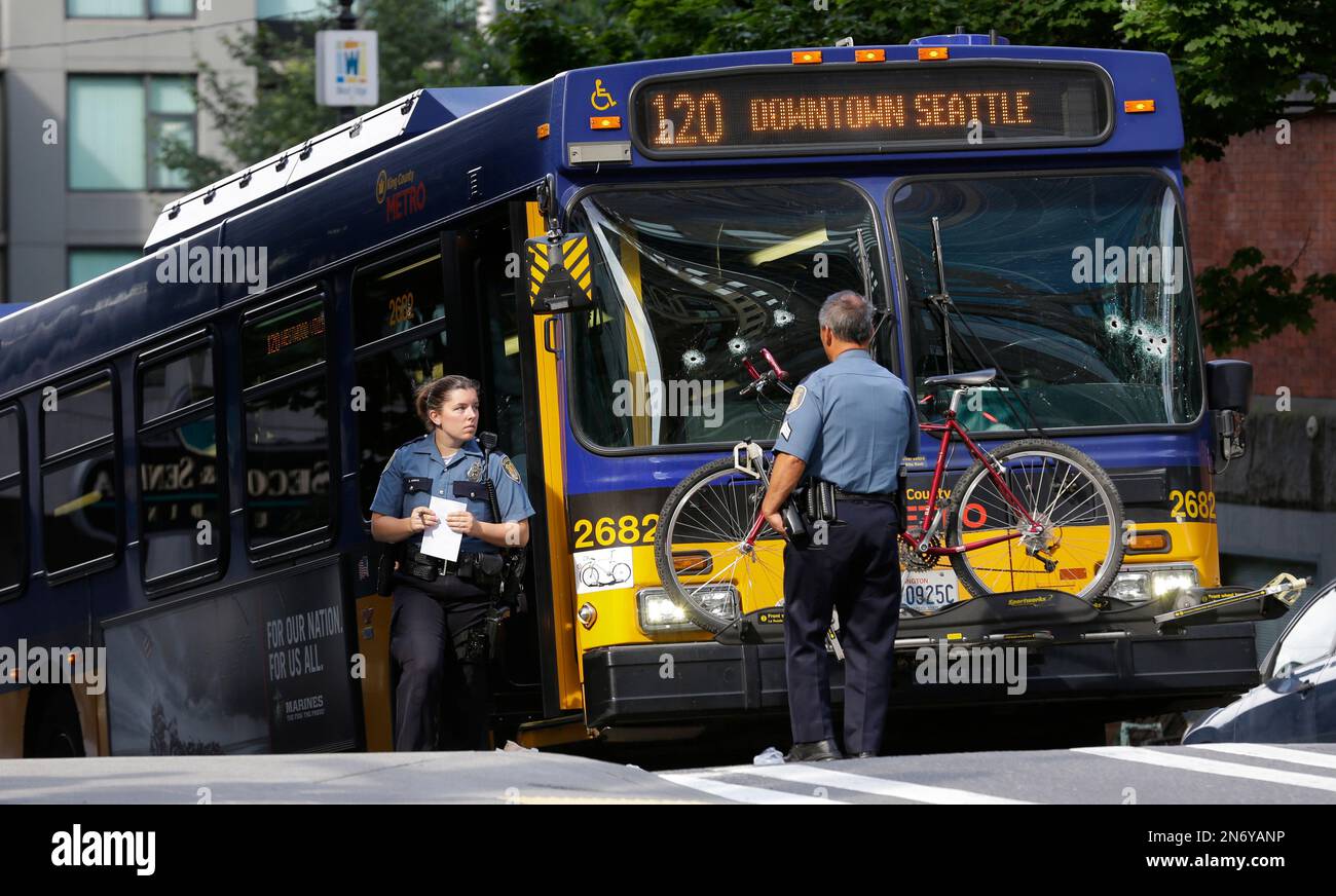 Seattle Police officers stand next to a King Co. Metro bus with multiple bullet holes in its ...