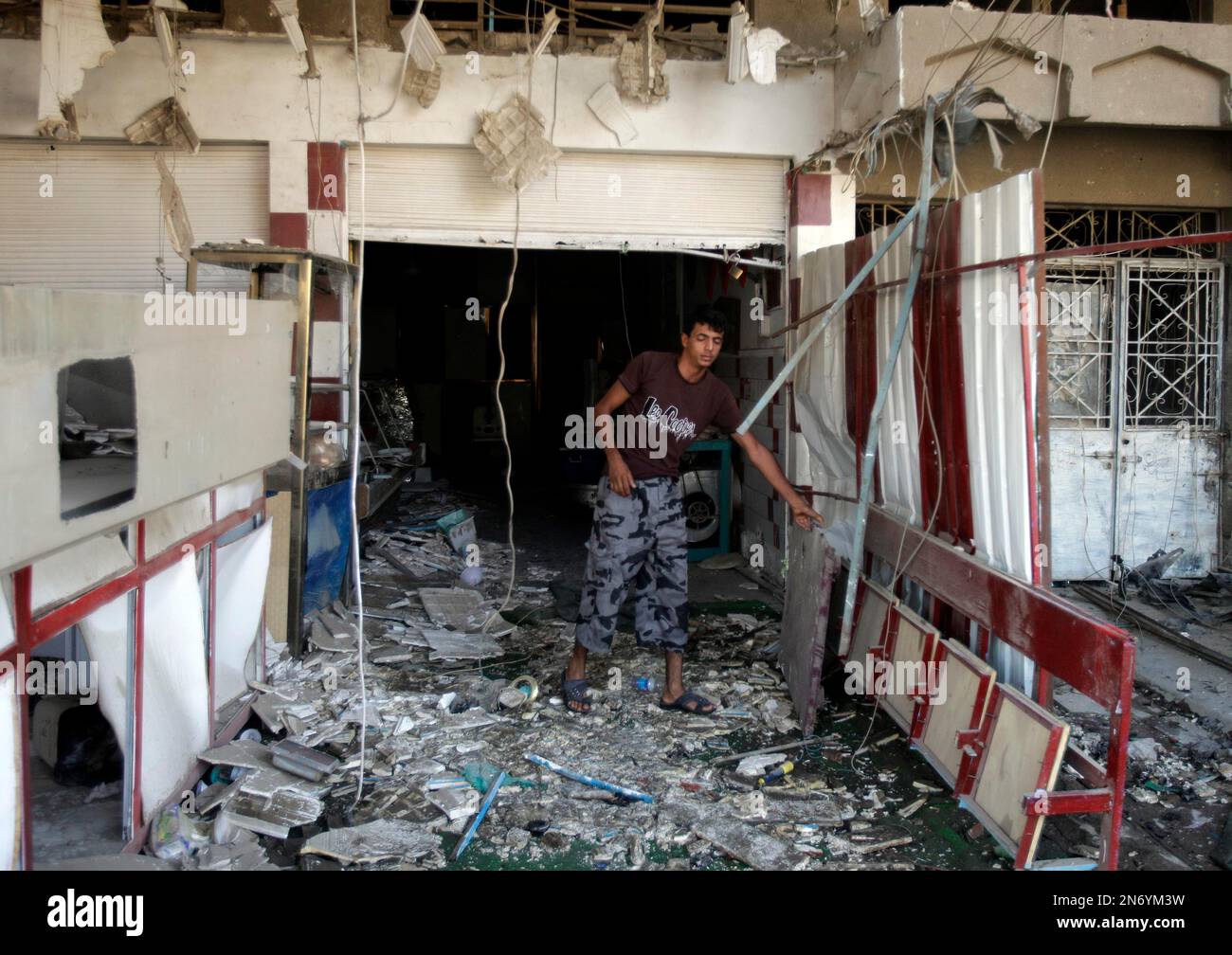 A man inspects the aftermath of a car bomb attack at a convenience store at the Shaab ...