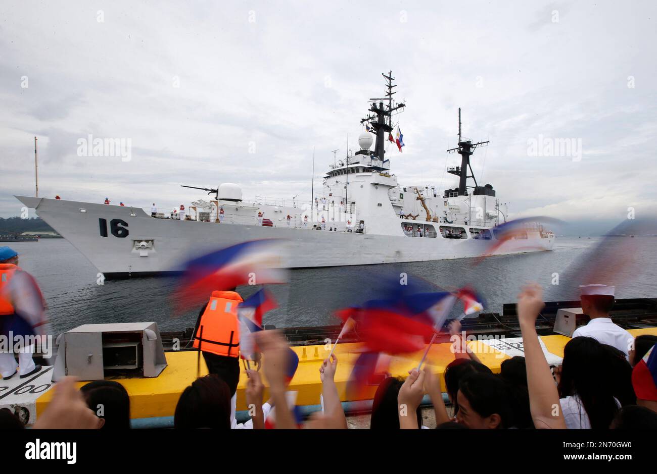 Students and other guests wave Philippine flags to welcome the second ...