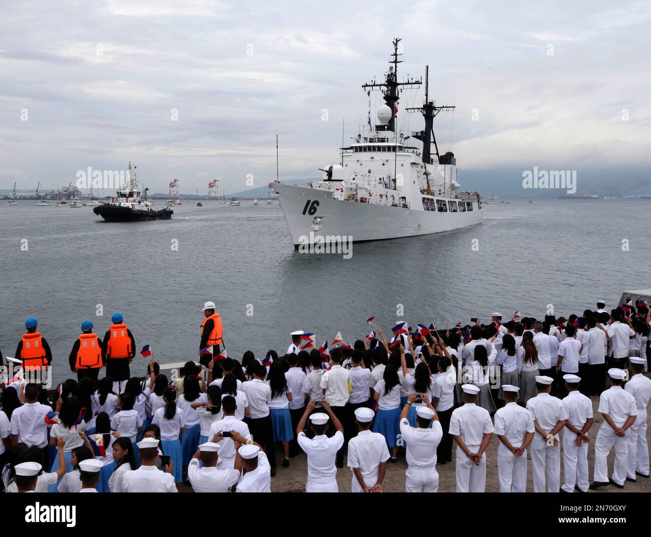 Students and other guests wave Philippine flags to welcome the second ...