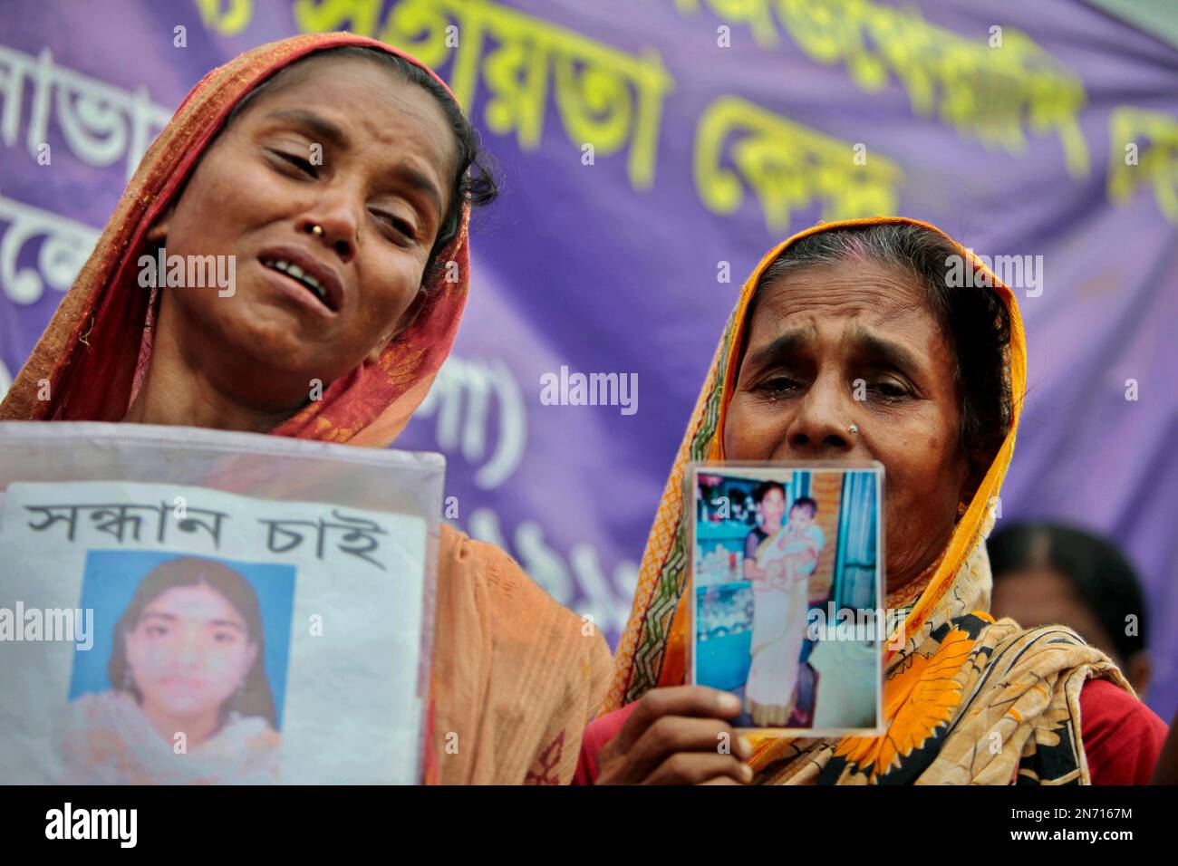 Bangladeshi mothers cry for their missing ones while holding their photos at the site of the ...