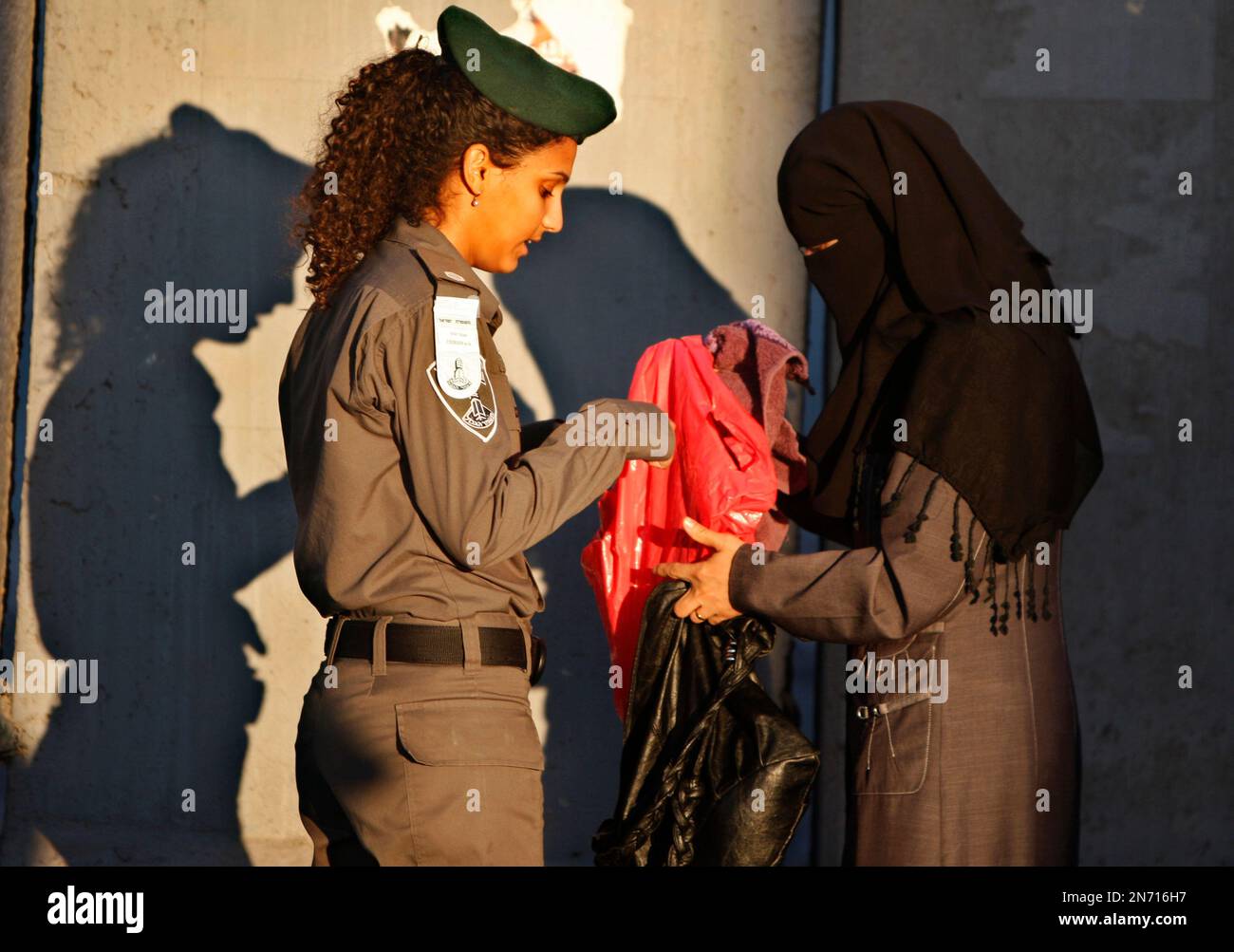 An Israeli border police officer checks a bag of a Palestinian woman as ...
