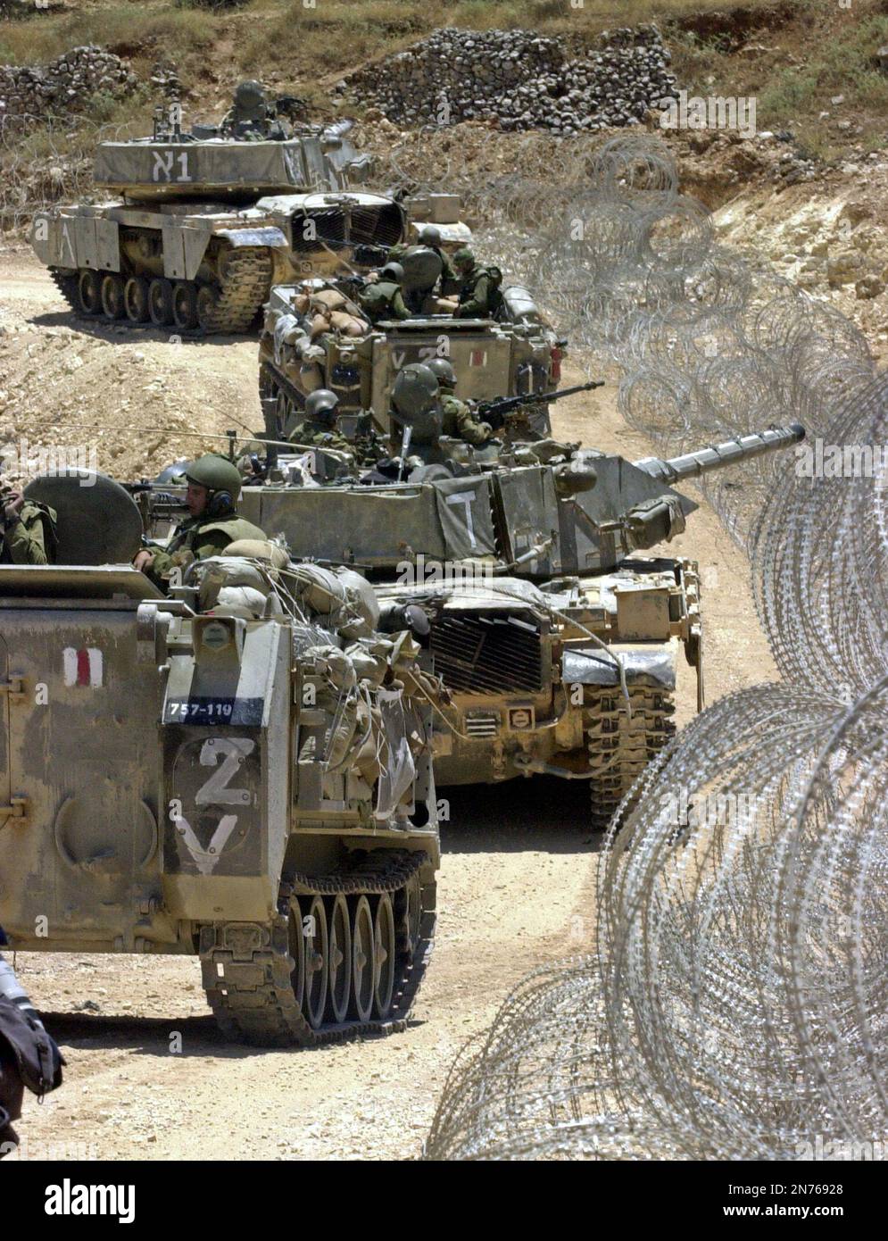 Israeli army tanks and armored personnel carriers pass next to razor ...
