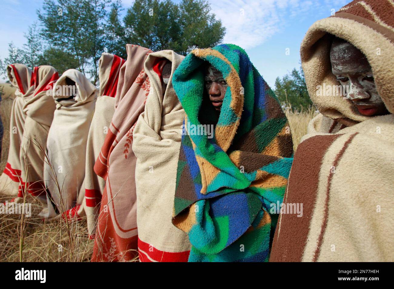 Xhosa boys covered with a blankets and smeared with chalky mud sit in a ...