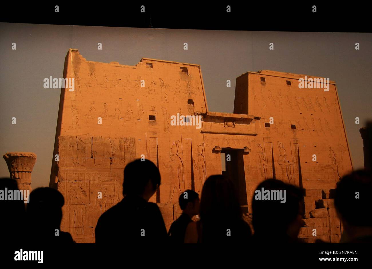 People are silhouetted against an ancient Egyptian building during a ...