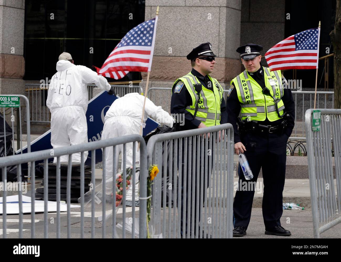 Boston police officers stand guard as investigators in protective suits ...