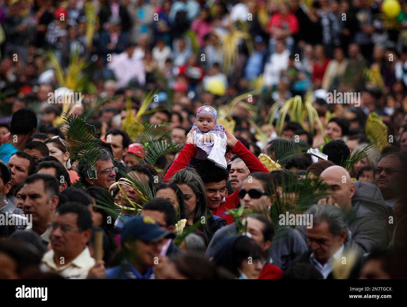 A man holds up a baby during Palm Sunday Mass at the Baby Jesus Church ...