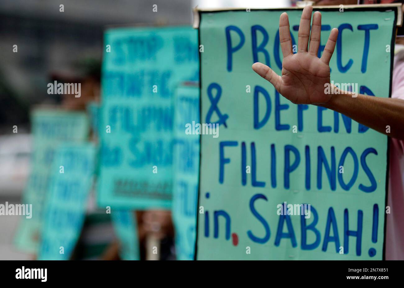 A Filipino activist raises her hand in front of slogans during a rally ...