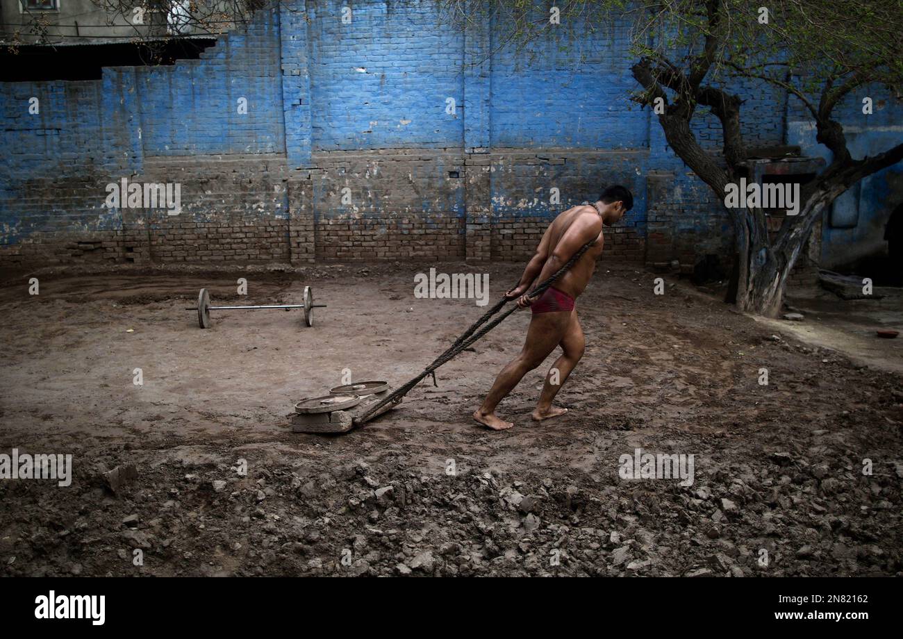 A Pakistani Kushti wrestler prepares the soil in the ring, prior to a ...