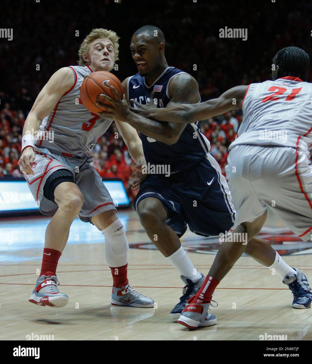 Nevada's Malik Story, middle, drives between New Mexico's Hugh ...