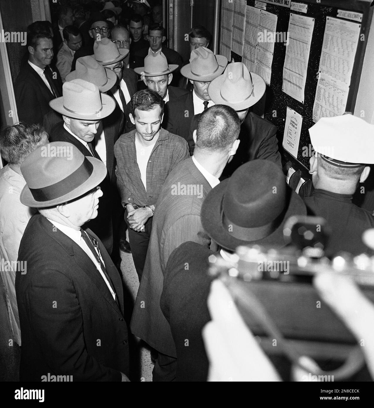 Lee Harvey Oswald, center, is shown in custody at a Dallas police ...