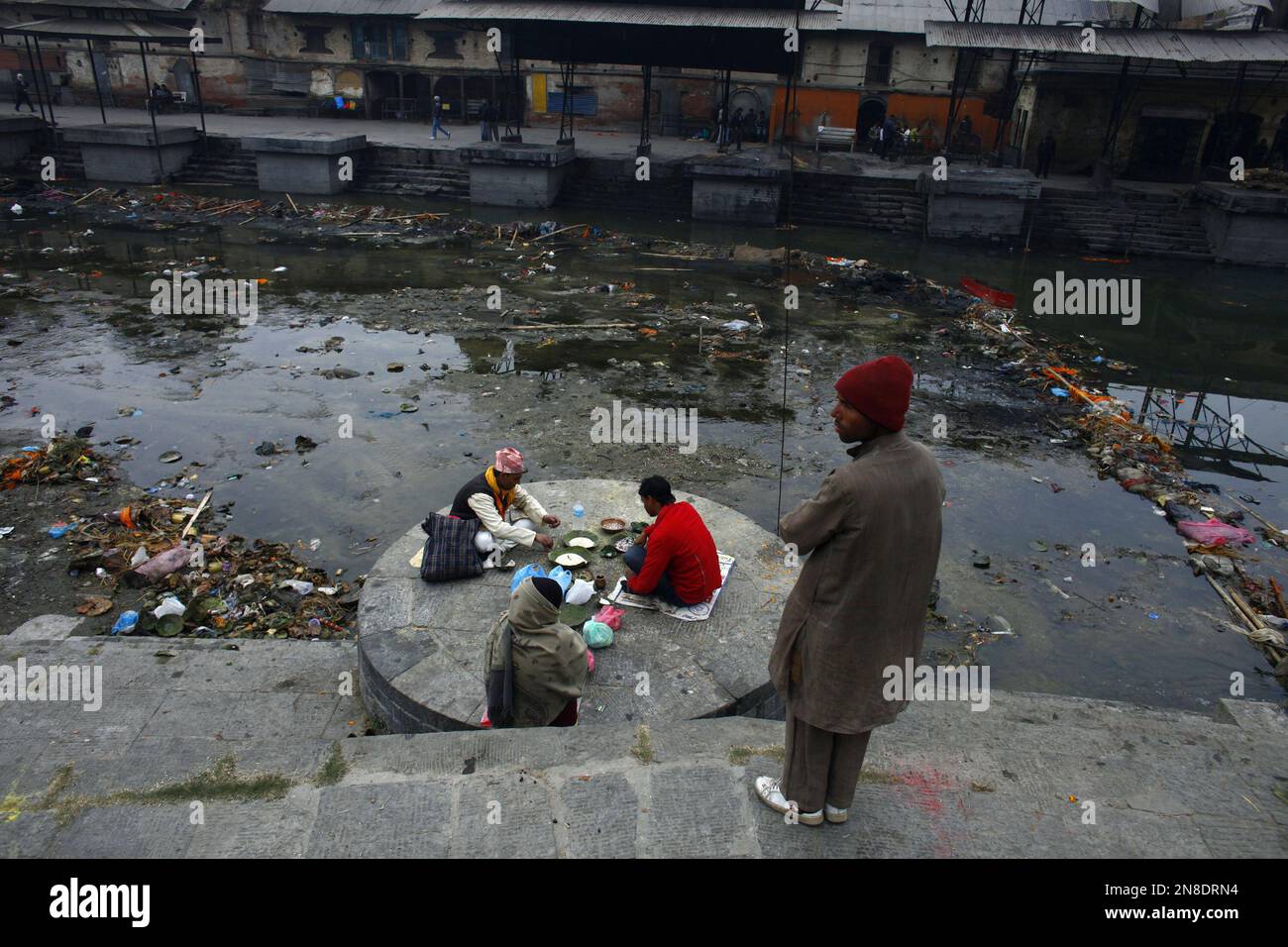 A Nepalese Hindu priest , left, assists devotees in performing rituals ...