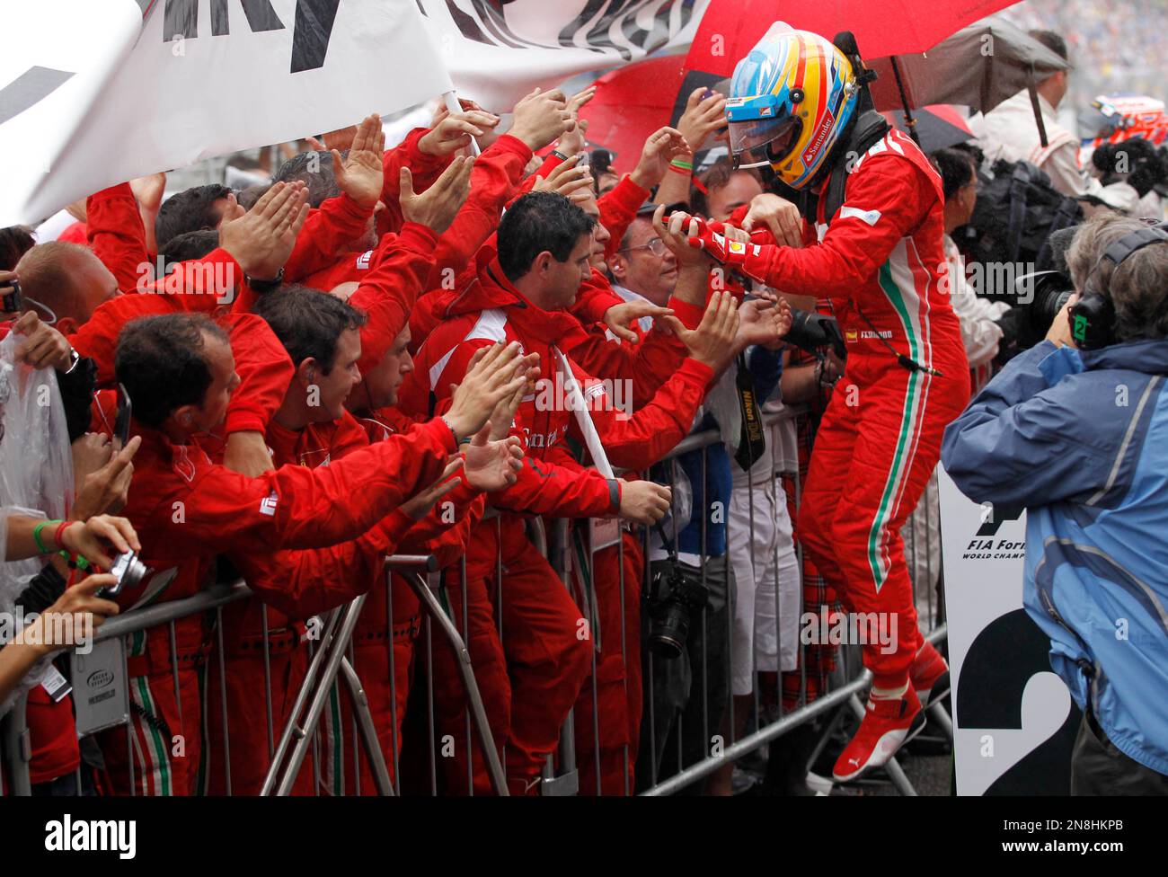 Teammates greet Ferrari driver Fernando Alonso of Spain after he ...