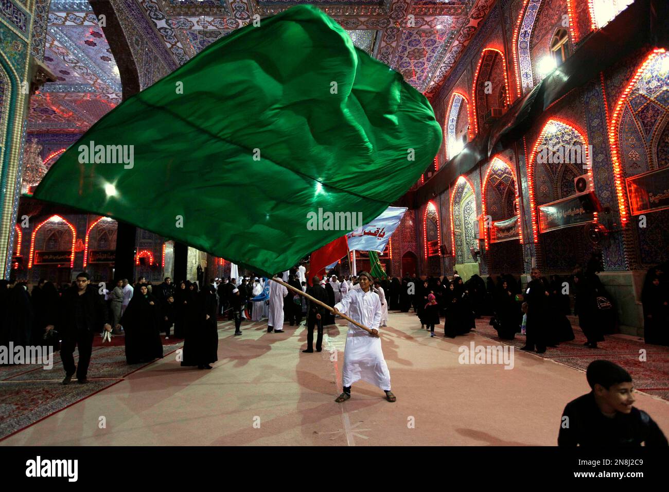 A Shiite Muslim worshipper waves a green flag, the traditional color of ...