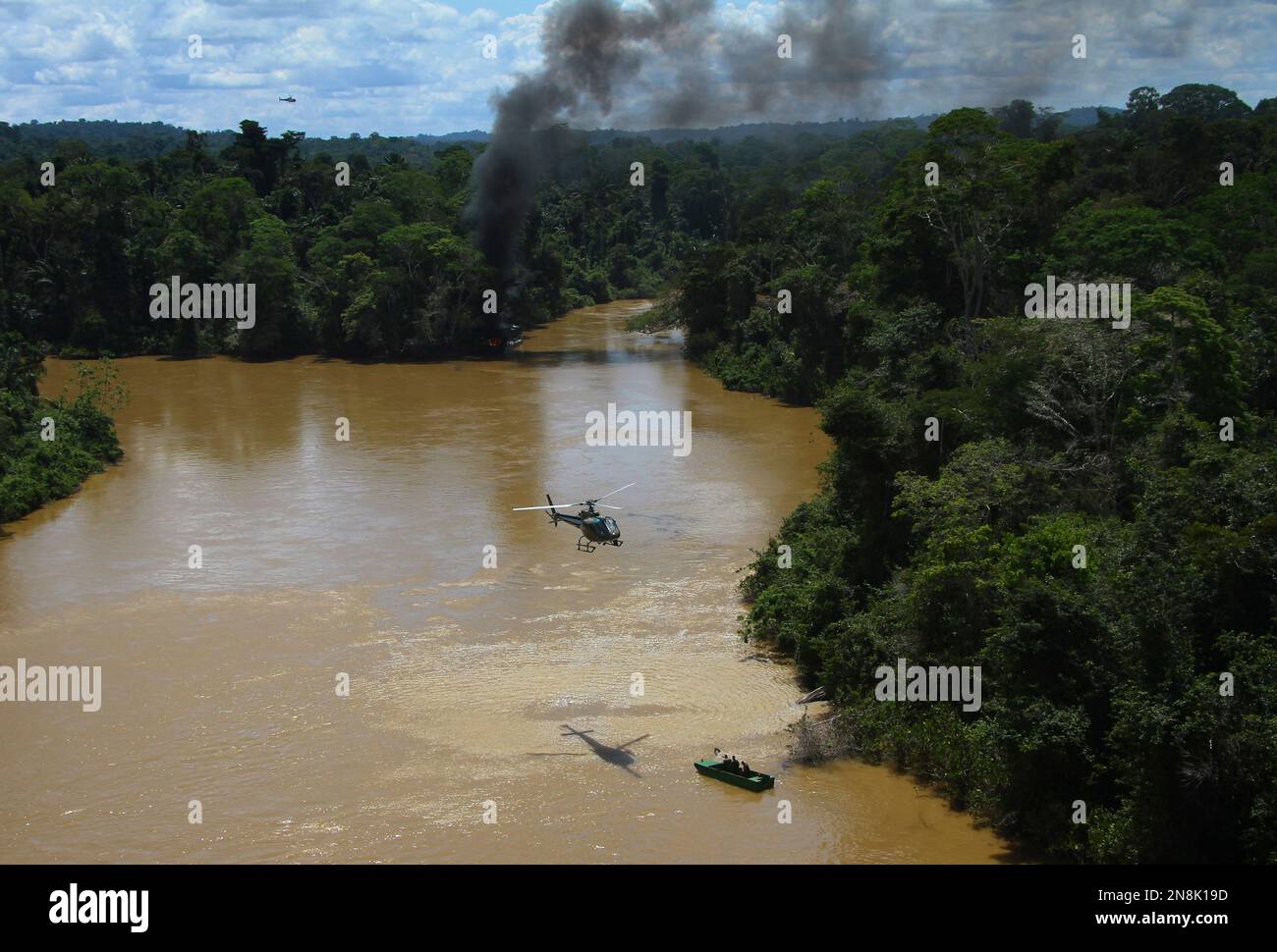Smoke and flames rises from a dredging barge on the Uraricoera River ...