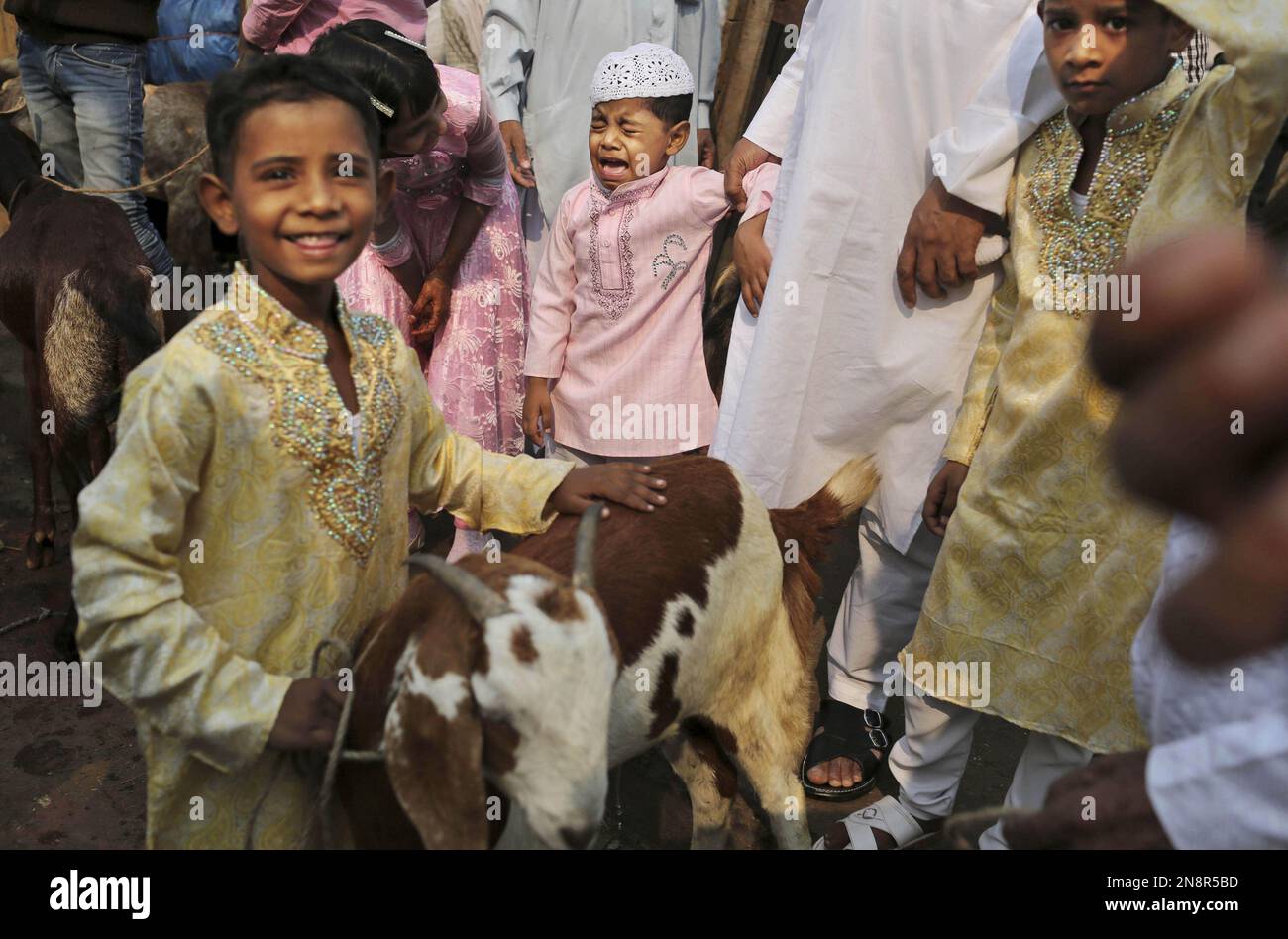 A young Indian Muslim boy cries as his father tries to get him to help ...