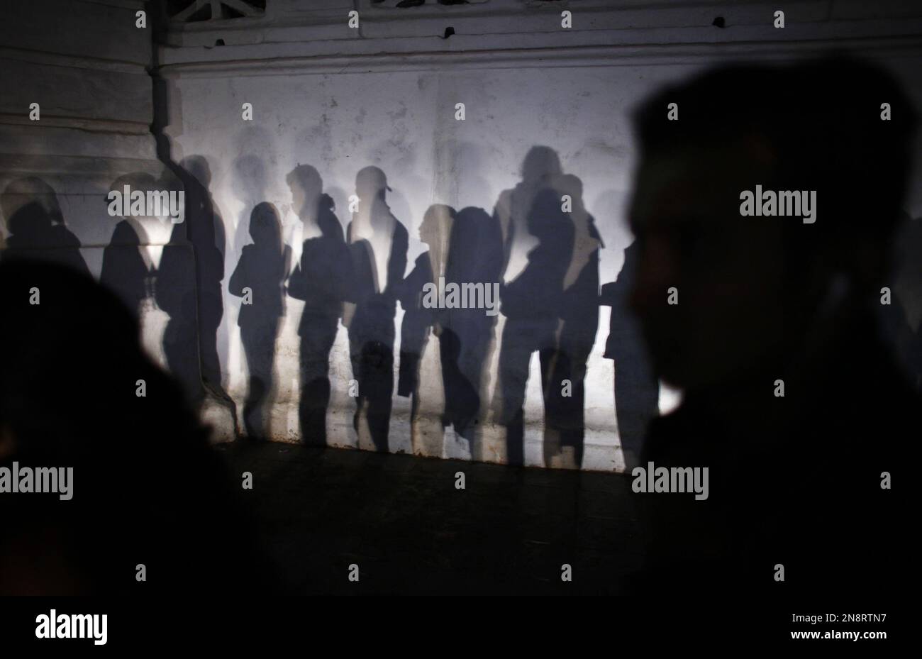 Nepalese devotees, their shadows on the wall, queue up to offer prayers ...
