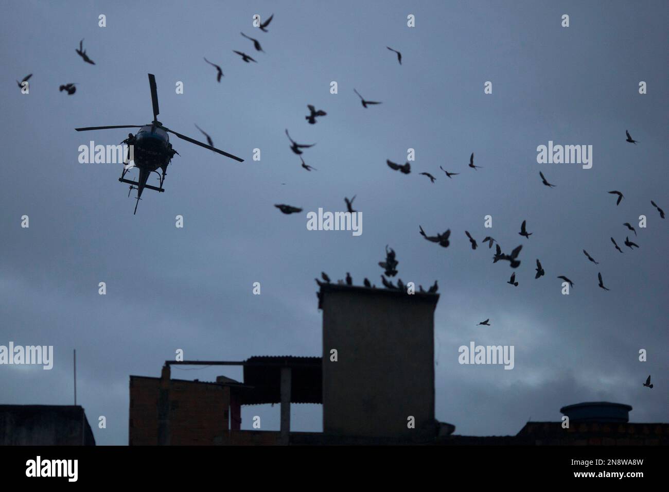A police helicopter flies over the Maguinhos slum during an operation ...