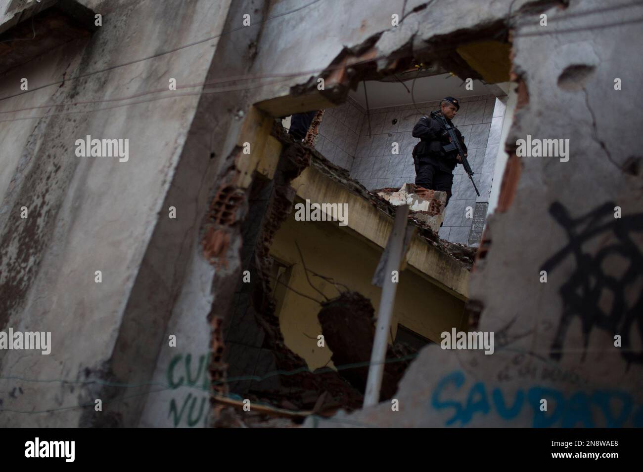 A Police officer patrols inside a destroyed house in the Maguinhos slum ...