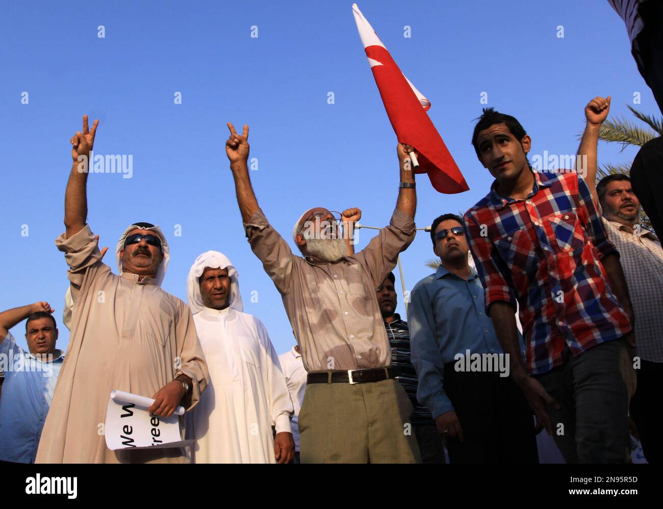 Bahraini men gesture and wave national flags as they chant anti ...