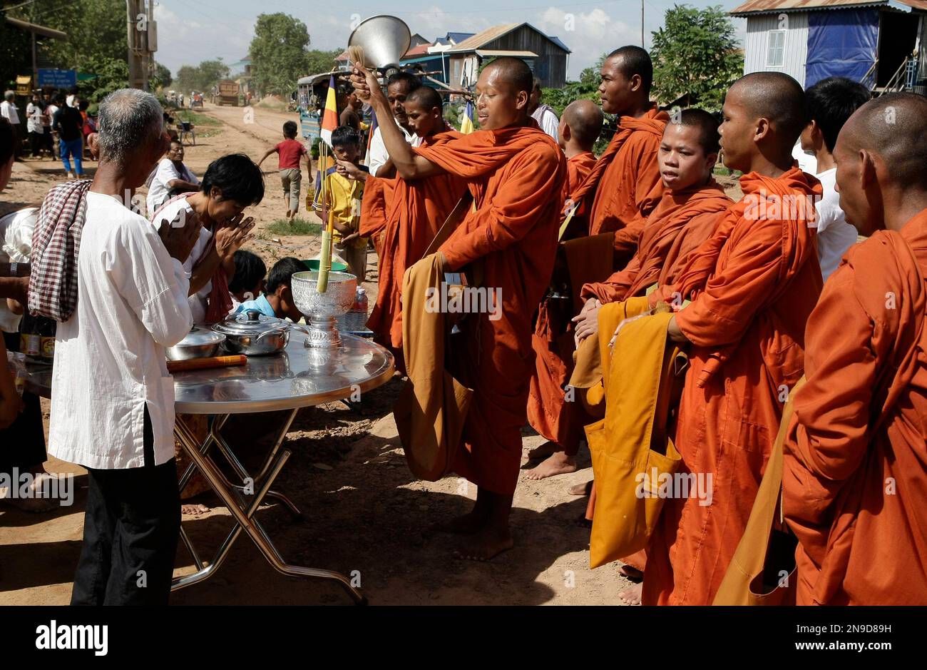 Cambodian residents, left, offer some food to Buddhist monks along the ...