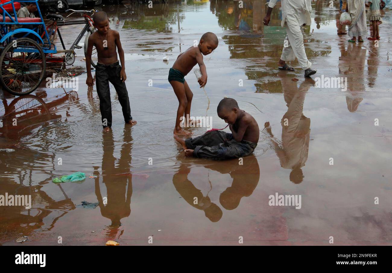 Children play in a water puddle left after a spell of rain in New Delhi ...