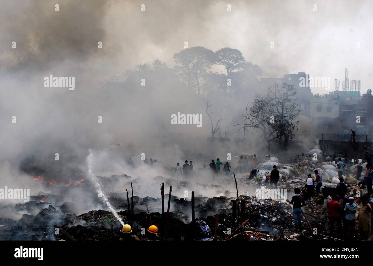 Indian firefighters spray water as they try to douse a fire in a shanty ...