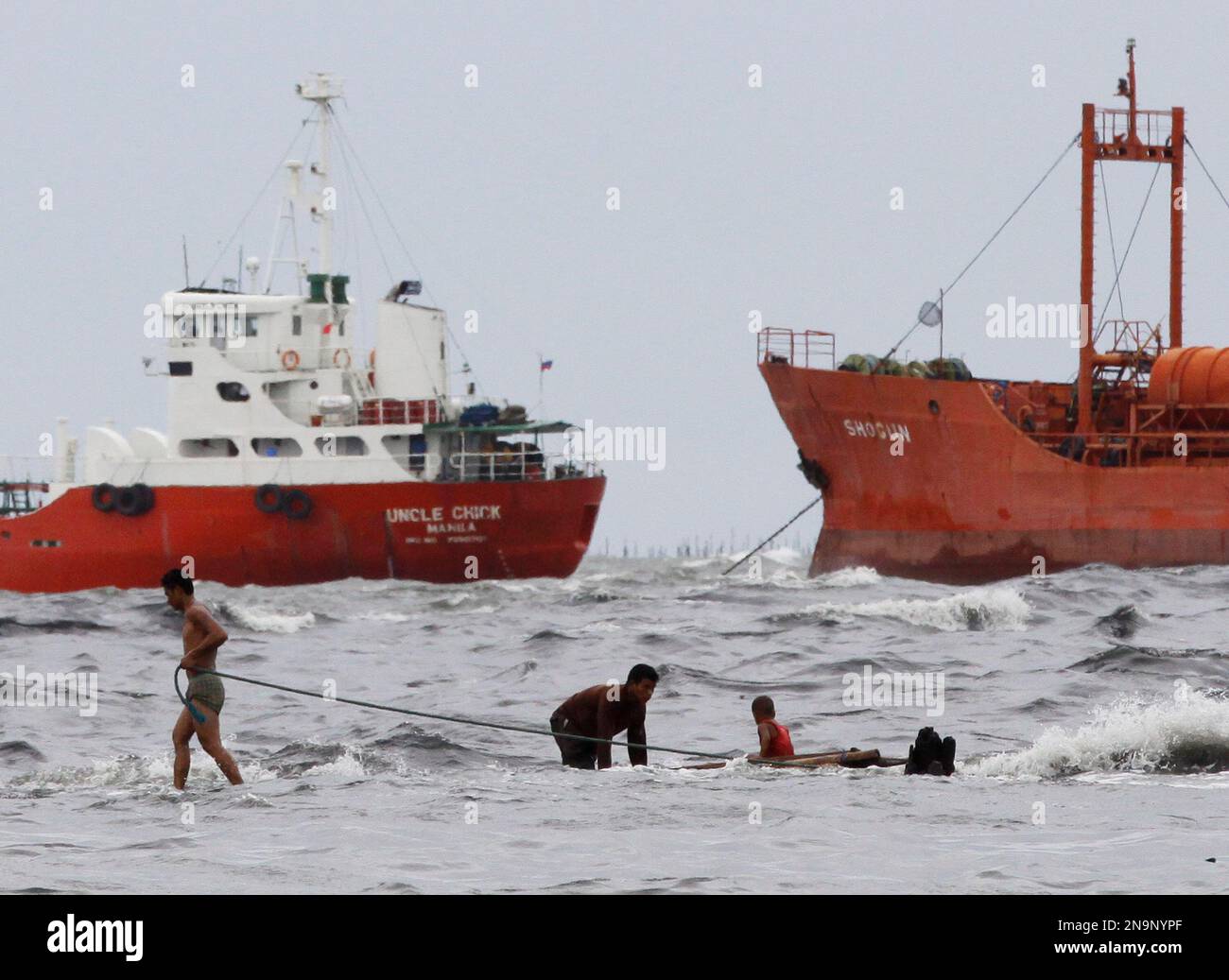 A man pulls a rope as another one secures his son in a raft in a ...