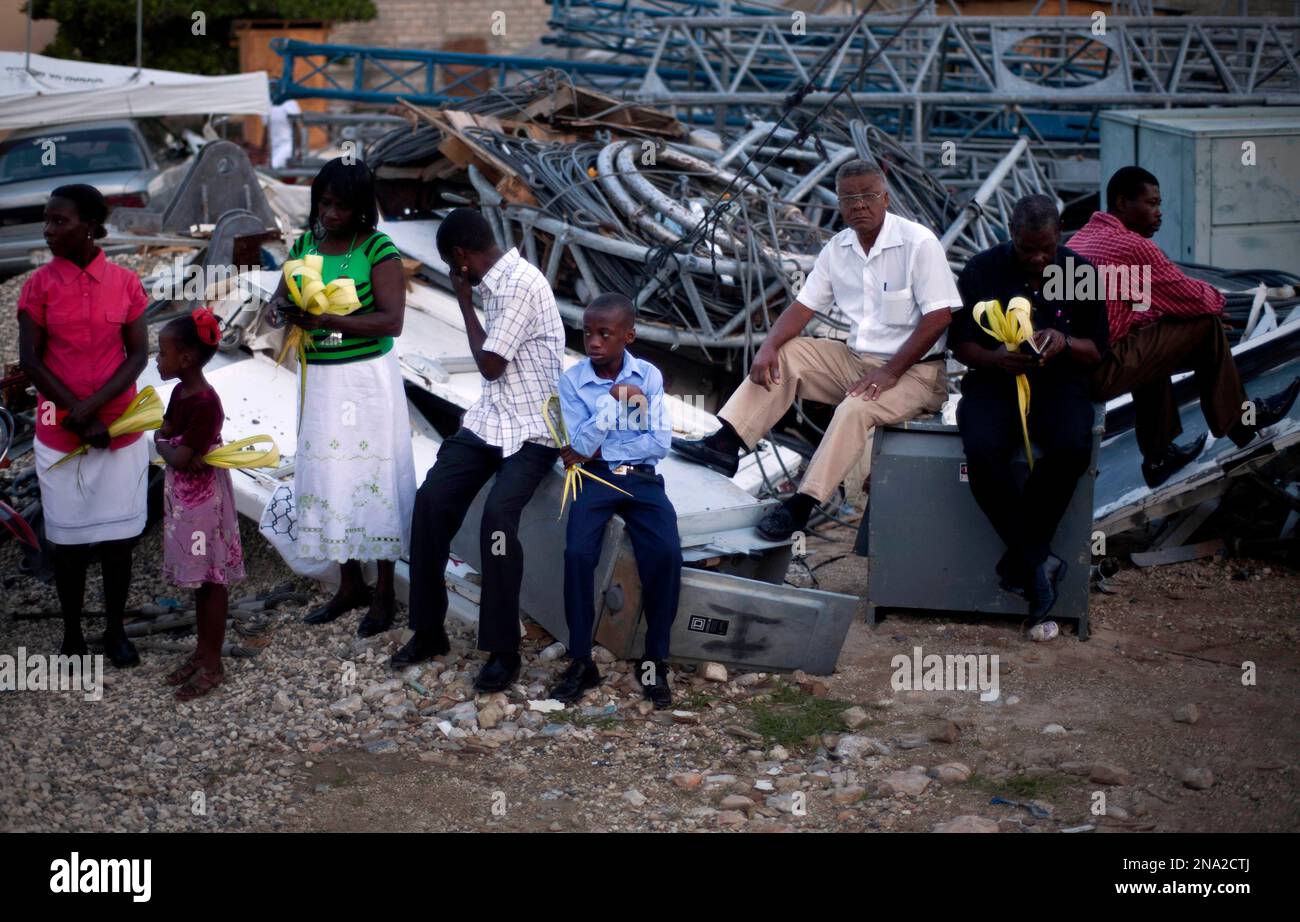 People sit on items that were discarded after the earthquake during an ...