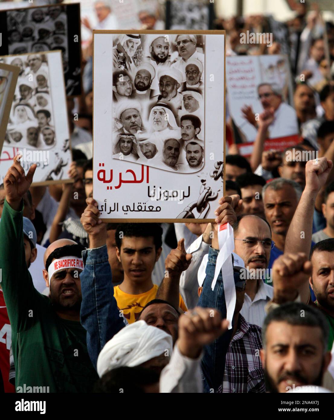 Bahraini anti-government protesters chant and raise signs during a ...