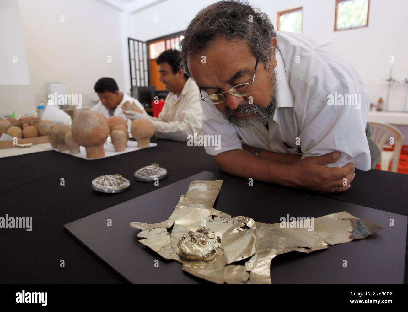 Peru's archaeologist Walter Alva watches a diadem that was discovered ...