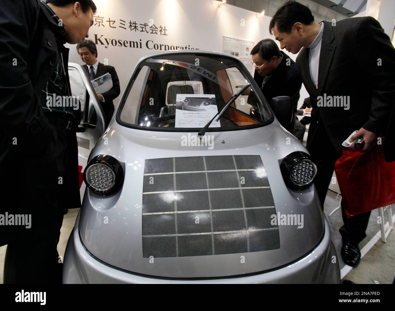 Visitors inspect a mini-electric vehicle T-10 attached with solar ...