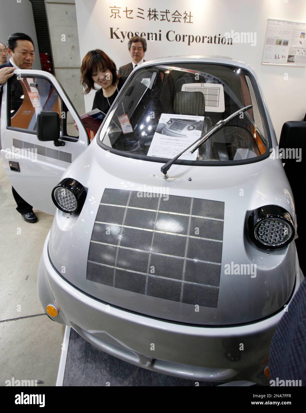 Visitors inspect a mini-electric vehicle T-10 attached with solar ...