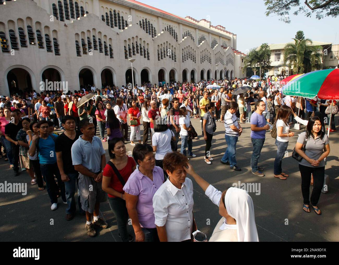Catholic nuns mark the foreheads of devotees with black ashes in the ...
