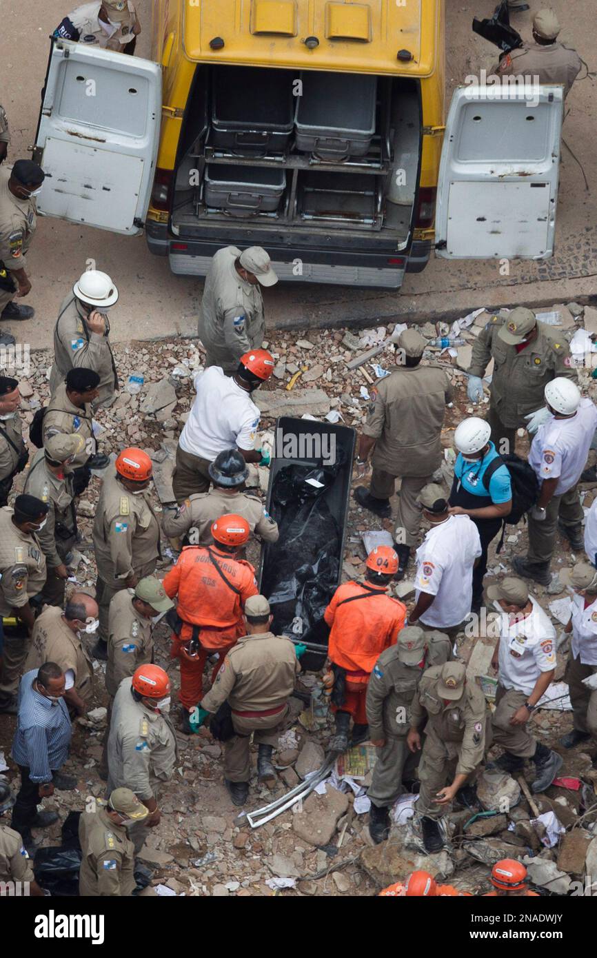 Rescue workers carry the body of a victim after a building collapsed in ...