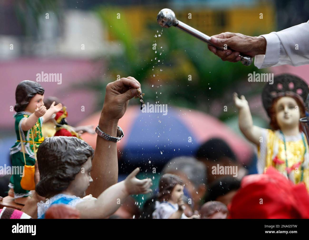 A Roman Catholic lay leader sprinkles holy water at statues of the Holy ...