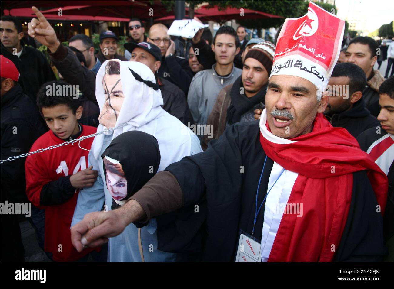A Tunisian dressed as a judge, right, leads a chained demonstrator ...