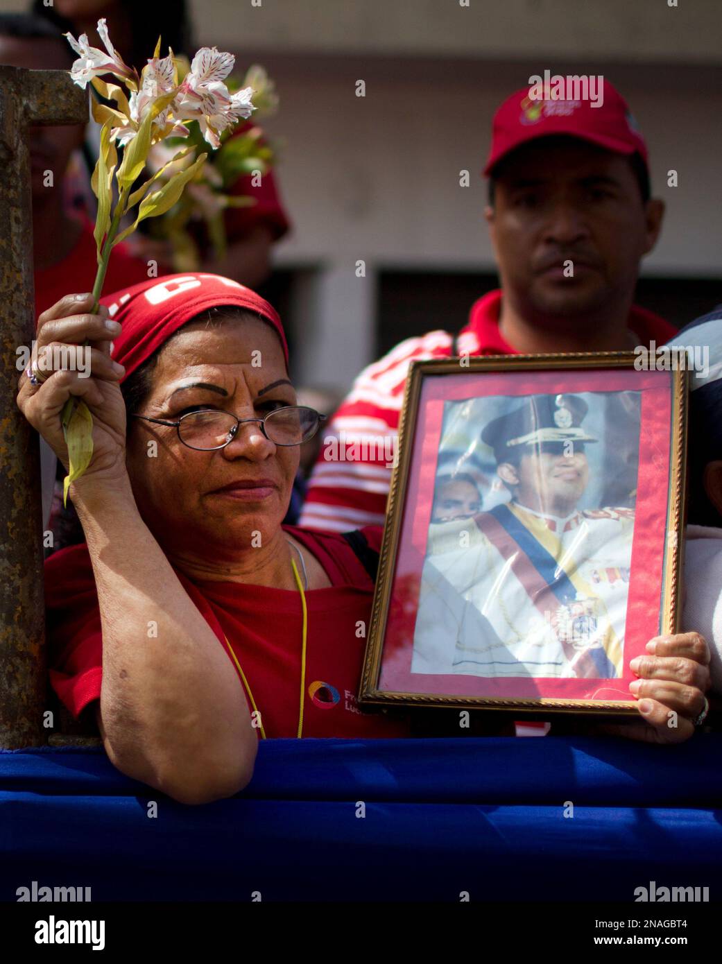 A woman holds a picture of Venezuela's President Hugo Chavez as she ...