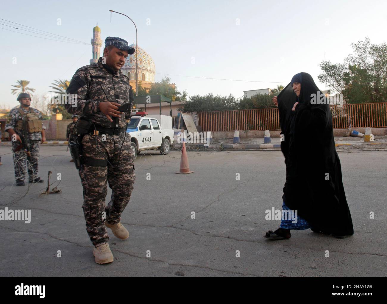 An Iraqi police officer uses a bomb detector to searches a woman ...