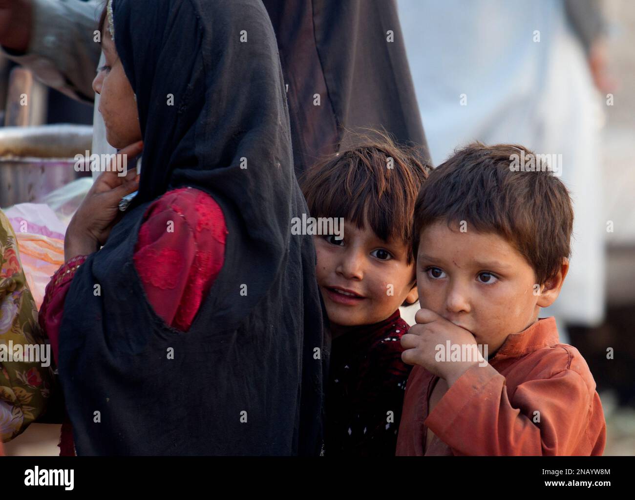 Poor Pakistani children wait to buy candies from a vendor on Monday ...