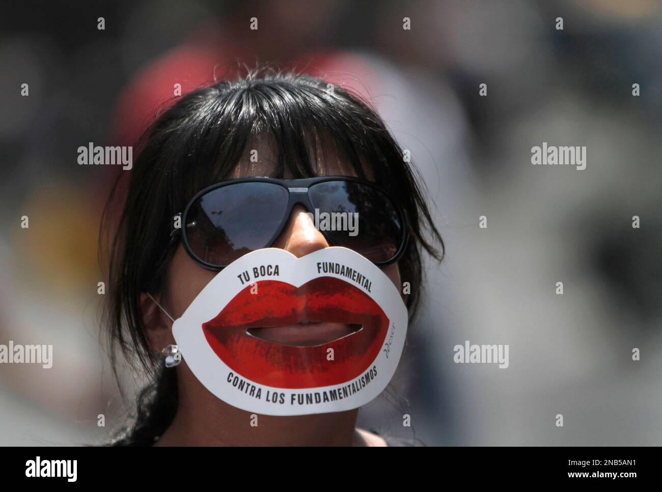 An activist, wearing a mask that reads in Spanish "Your mouth is ...