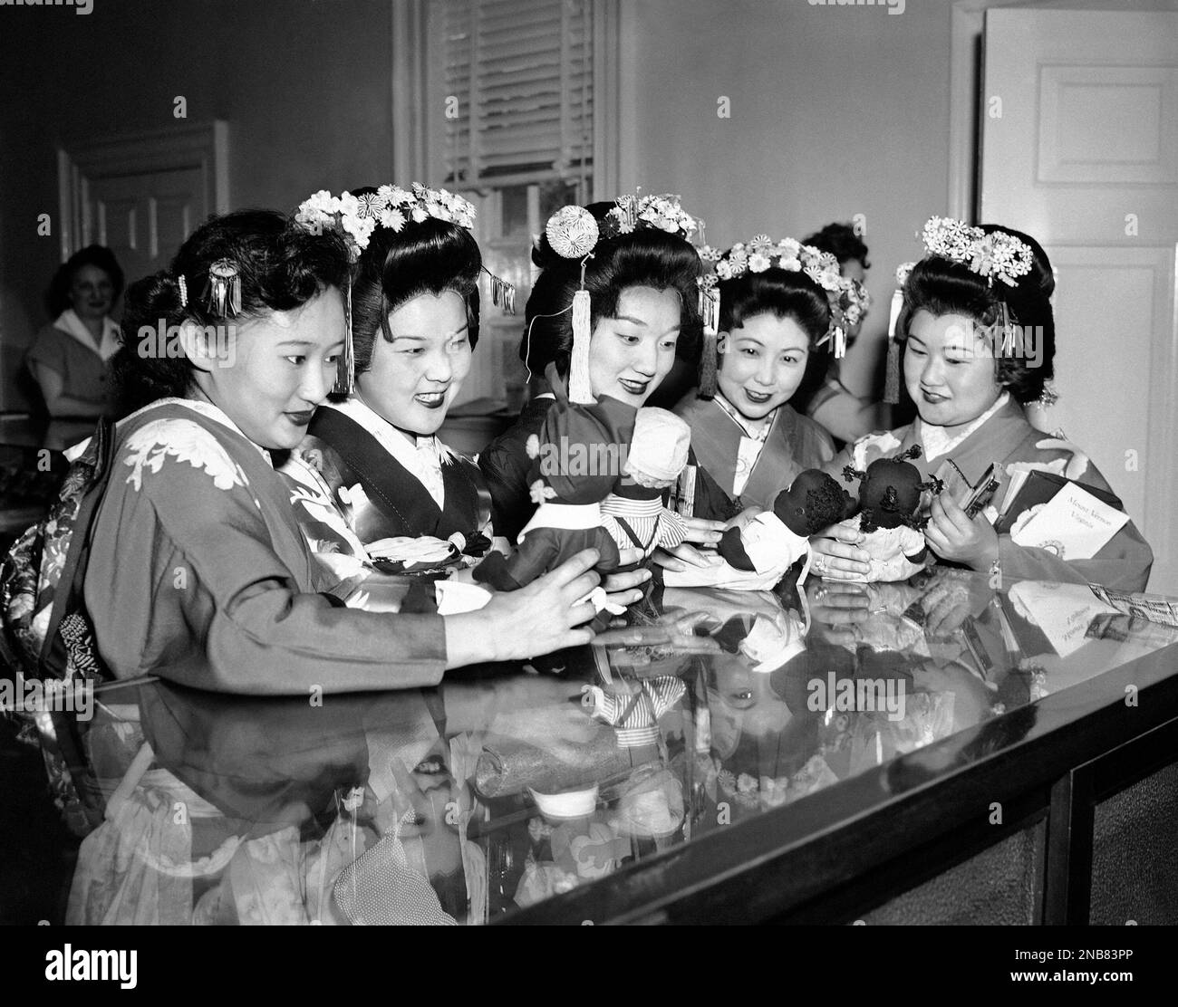 The Japanese Geisha girls are fascinated by pickaninny dolls on display ...