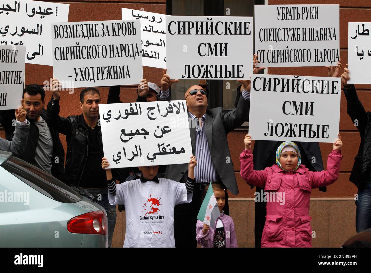 Anti-Syrian regime protesters hold placards in in Arabic and Russian ...