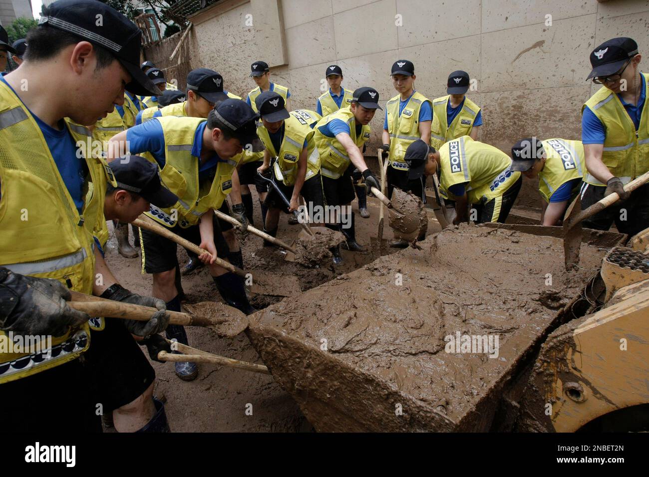South Korean police officers remove mud after a landslide, caused by ...