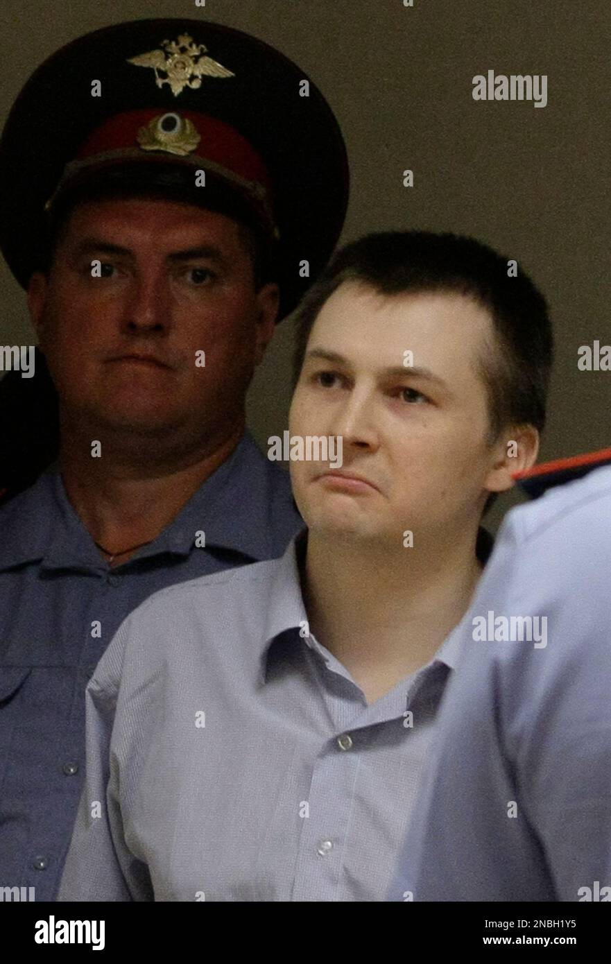 Lev Molotkov, a member of the country's most vicious neo-Nazi gang stands behind police officers ...