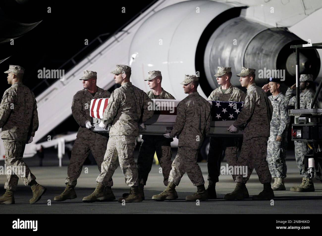 A Marine carry team carries the transfer case containing the remains of ...