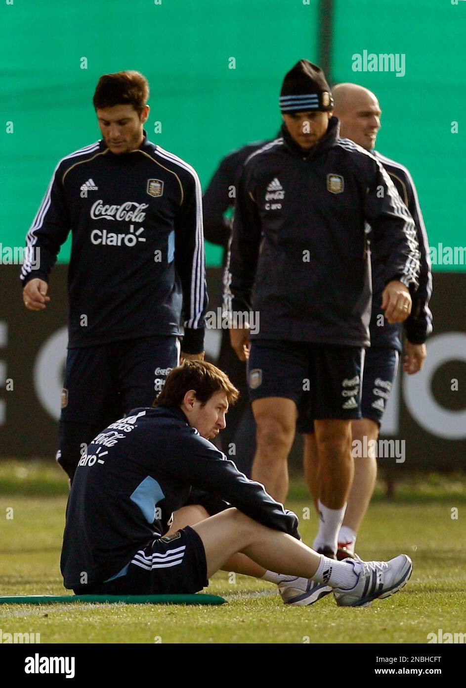 Argentina's Lionel Messi sits on the field as teammates Javier Zanetti ...