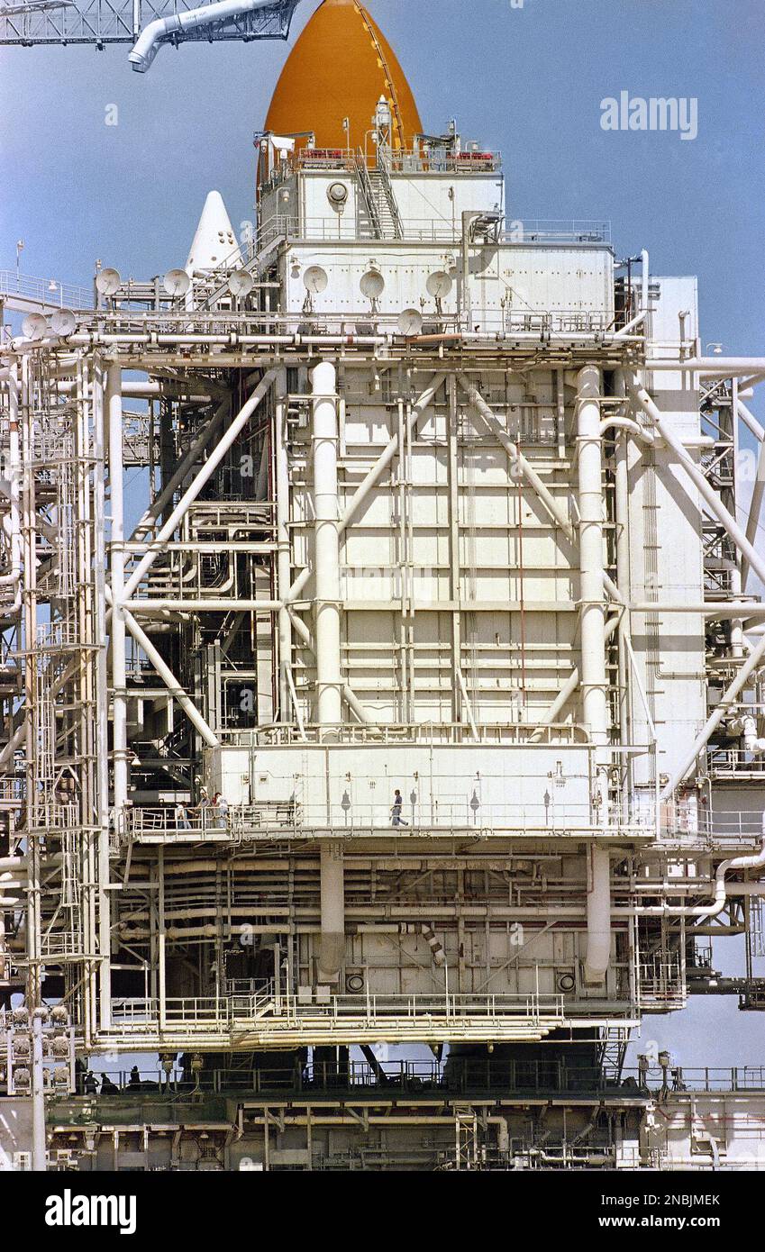 NASA workers walk across the rotating service structure that is ...