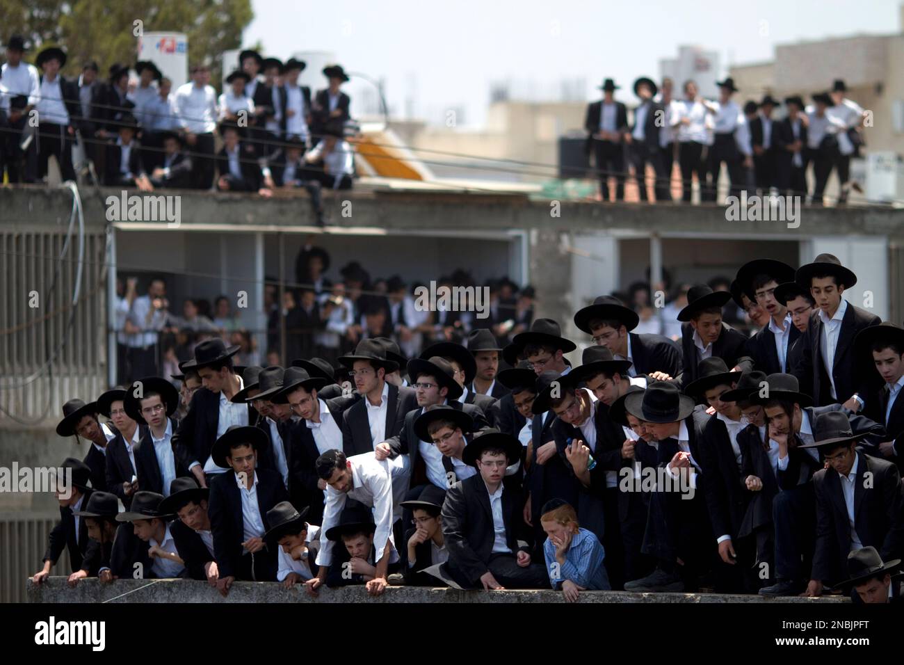 Ultra-Orthodox Jewish men gather on roof tops to watch the funeral of ...