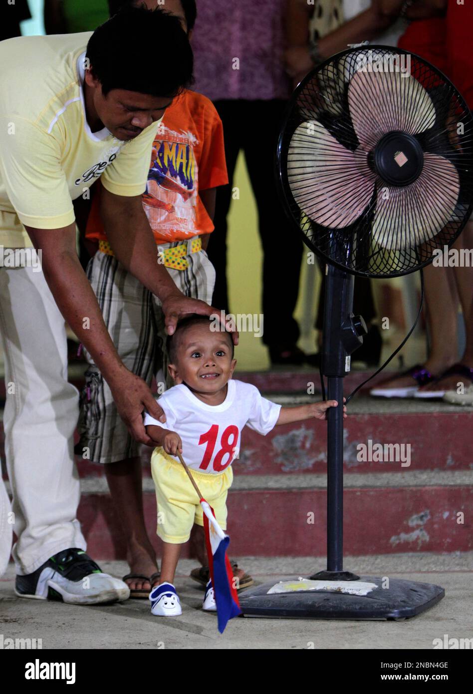 Junrey Balawing holds a Philippine flag as he is assisted by his father ...
